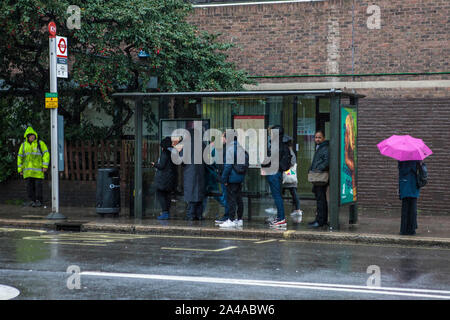 People queue in the rain for a bus on a wet Tuesday morning at the ...