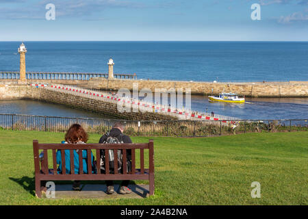 A pleasure cruiser leaves Whitby Harbour viewed from the high promenade ...