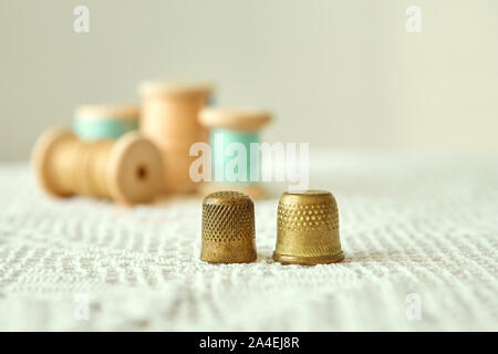 Thread bobbins and metal sewing thimbles in closeup Stock Photo - Alamy