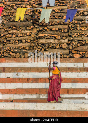 Indian female street cleaner sweeping the dusty streets beside bicycle ...