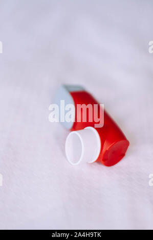 A still life of red and white asthma inhaler devise on a white ...