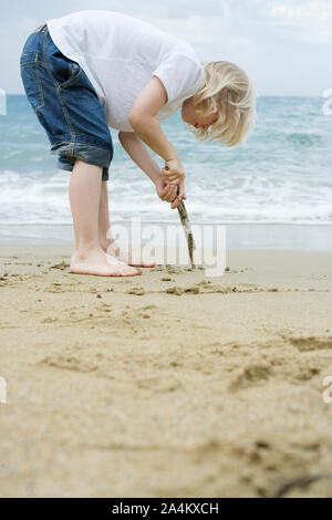 Child drawing in the sand with stick, cropped view of hand Stock Photo ...