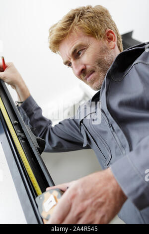 Construction worker repairing window in house Stock Photo - Alamy