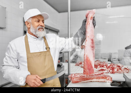 Male slaughterhouse worker showing beef chunk in meat storage Stock ...