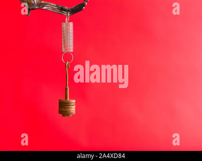 Masses hanging on a stretched spring isolated on a red background ...