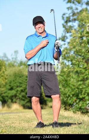 male professional golfer posing with a golf club in a green field on a ...