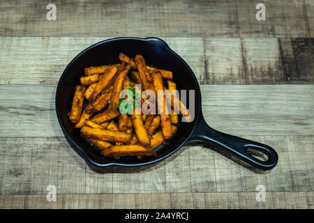 Pan of French fries with ketchup and dark beer on wooden table close up ...
