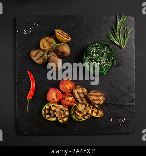chuka salad and baked vegetables on a black board decorated with pepper ...