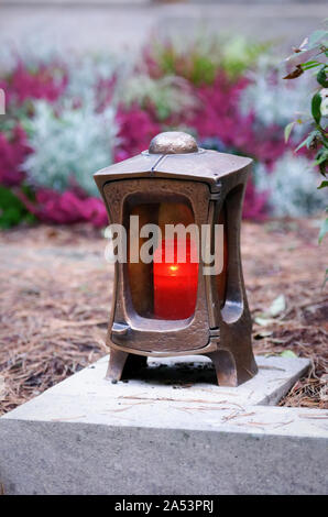 Grave light with burning candle on a grave with flowers Stock Photo - Alamy