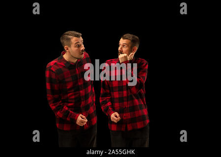 Young handsome man arguing with himself on black studio background ...