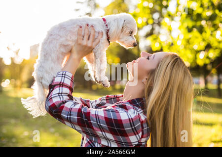 Woman embracing puppy dog outdoor. Happy girl gets lovely dog, plays ...