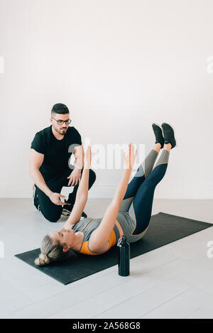 Fitness instructor observing woman doing lunges in studio Stock Photo ...
