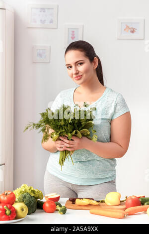 Cooking Meal. Chubby girl standing in kitchen with tape measure and ...