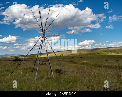 Nez Perce teepee frames with white billowing clouds and blue sky in ...