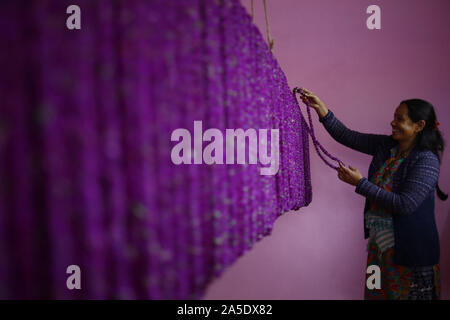 Bhaktapur, Nepal. 20th Oct, 2019. A woman hangs garlands made of ...