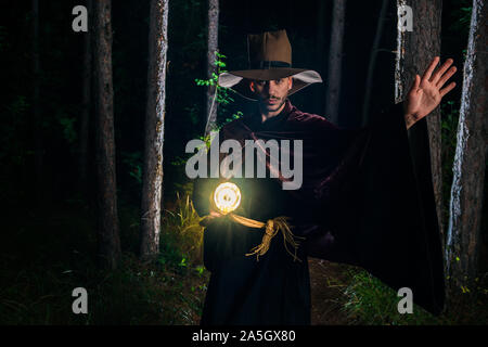 Man who is wearing wizard robes and casting glow spell with his magic ...