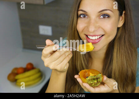 Healthy woman eating persimmon kaki fruit at home. Close up from above ...