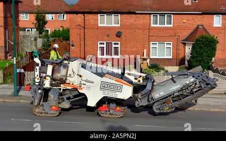 Road resurfacing. Road milling machine removing old pavement from a ...