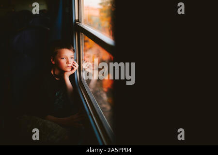 Thoughtful boy looking through train window Stock Photo - Alamy