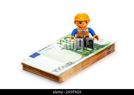 Minifigure toy worker model standing of a pilo of euro banknote, money ...