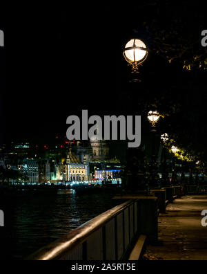 Ornate streetlights along Thames River at night with view of St Paul's ...