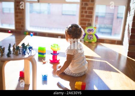 Adorable toddler building pyramid using hoops around lots of toys at ...