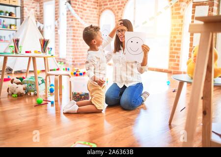 Beautiful psiychologist and toddler doing therapy around lots of toys ...