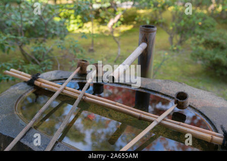 Japanese water basin, called a tsukubai, fed by a bamboo water pipe, or ...