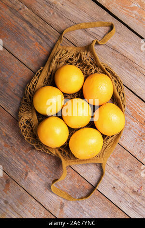 Fresh red grapefruit, mesh bag and herbs in sunlight. Top view, flat ...