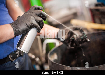 Car master mechanic repairer lubricates the screws with a machine parts ...