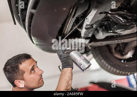 Car master mechanic repairer lubricates the screws with a machine parts ...