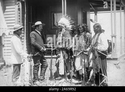 Three Cheyenne men wearing ceremonial clothing and holding rifles ...