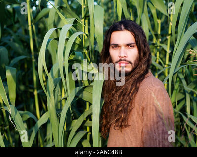 Young handsome man with long hair wearing santa claus hat over isolated ...