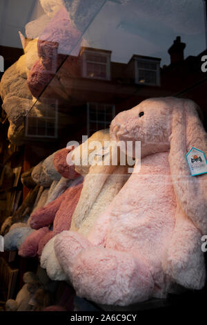 Toy rabbits in shop window display. Soft toys at sale on shelves in ...