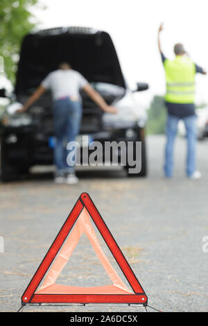 man waiting for technical support service sitting on the hood of an ...