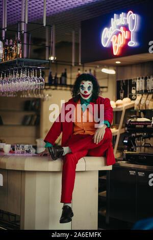 Cosplayer portrays a crazy clown against the background of the bar ...