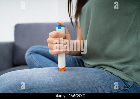An allergic woman injecting an adrenaline injection into her thigh ...