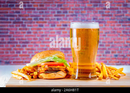 Hamburger, french fries and glass of cold beer on a white wooden ...