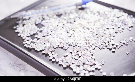 An abundance of white rhinestones with flat back on a black board ready ...