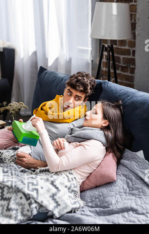 sick girlfriend taking napkin and boyfriend holding box in apartment ...