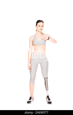 Young sportswoman with prosthesis looking at smartwatch while lying on ...