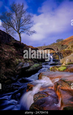 Three Shire Heads. A waterfall and packhorse stone bridge at Three ...