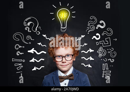 Clever child boy with light bulb and question marks on white background ...