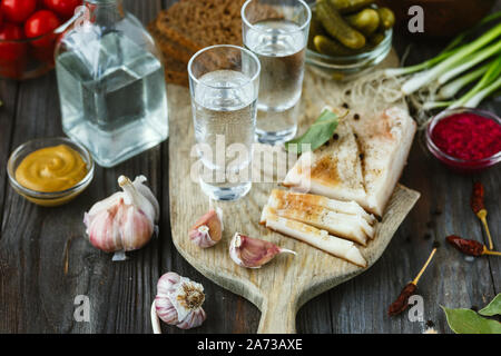 Vodka with lard, salted vegetables on wooden background. Alcohol pure ...