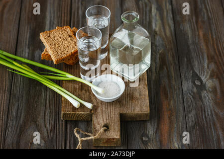 Vodka with green onion, bread toast and salt on wooden background ...