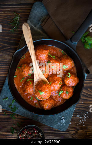 Homemade meatballs in tomato sauce. Frying pan on a wooden surface ...