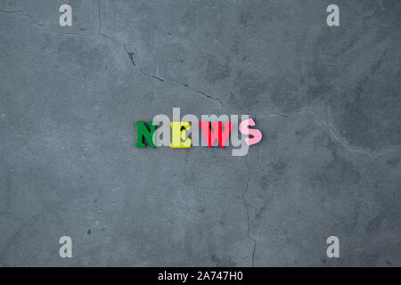 The multicolored news word is made of wooden letters on a grey ...