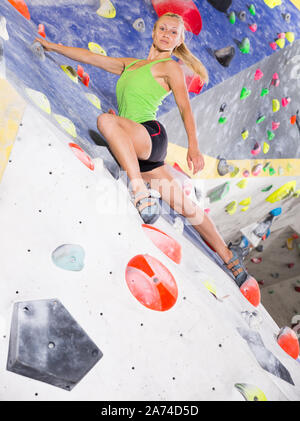 Female mountaineer practicing boulder climbing outdoor on large boulder ...