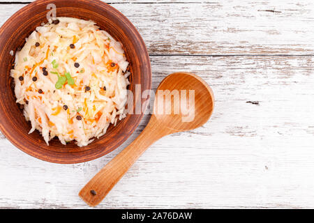 Woman with spoon and bowl of homemade sauerkraut at wooden table Stock ...