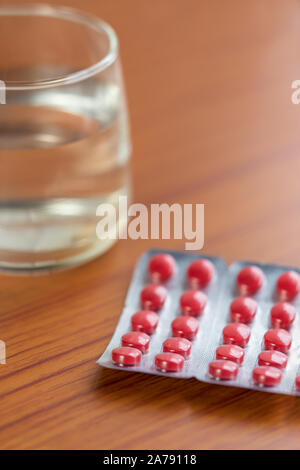 Medicine and water on table with sick person blurred in background ...